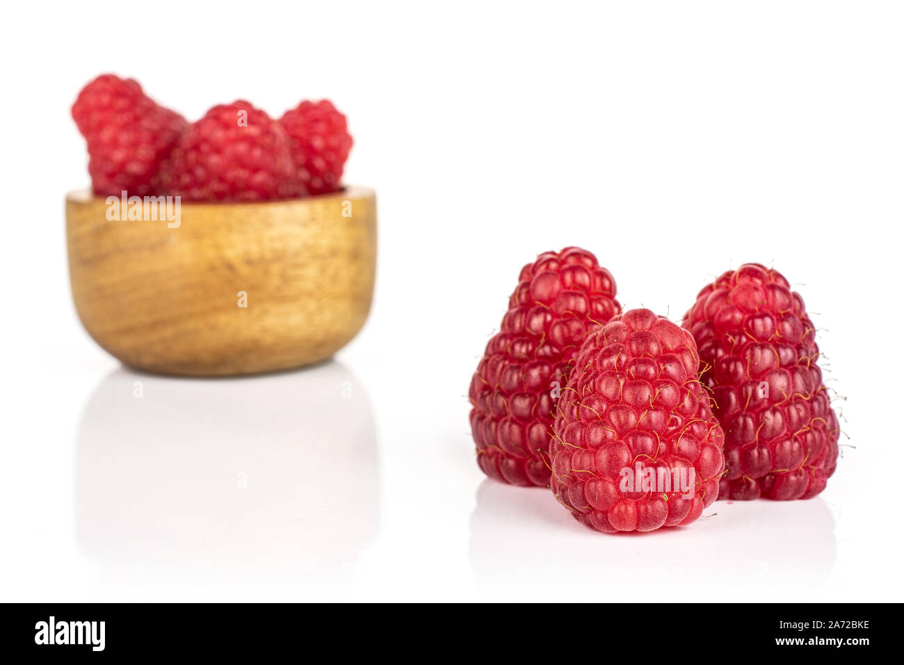 Group of six whole fresh red raspberry in tiny wooden bowl isolated on ...