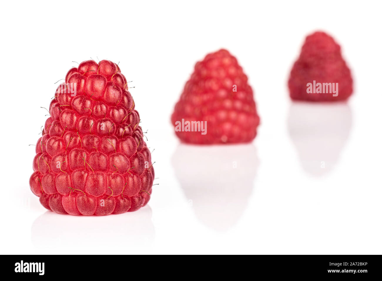 Group of three whole fresh red raspberry placed diagonally isolated on ...