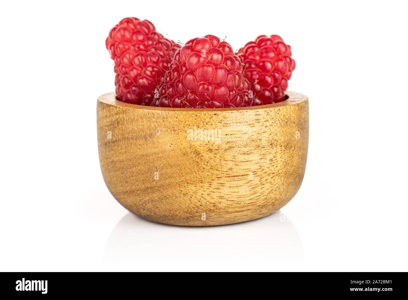 Group of three whole fresh red raspberry in tiny wooden bowl isolated ...