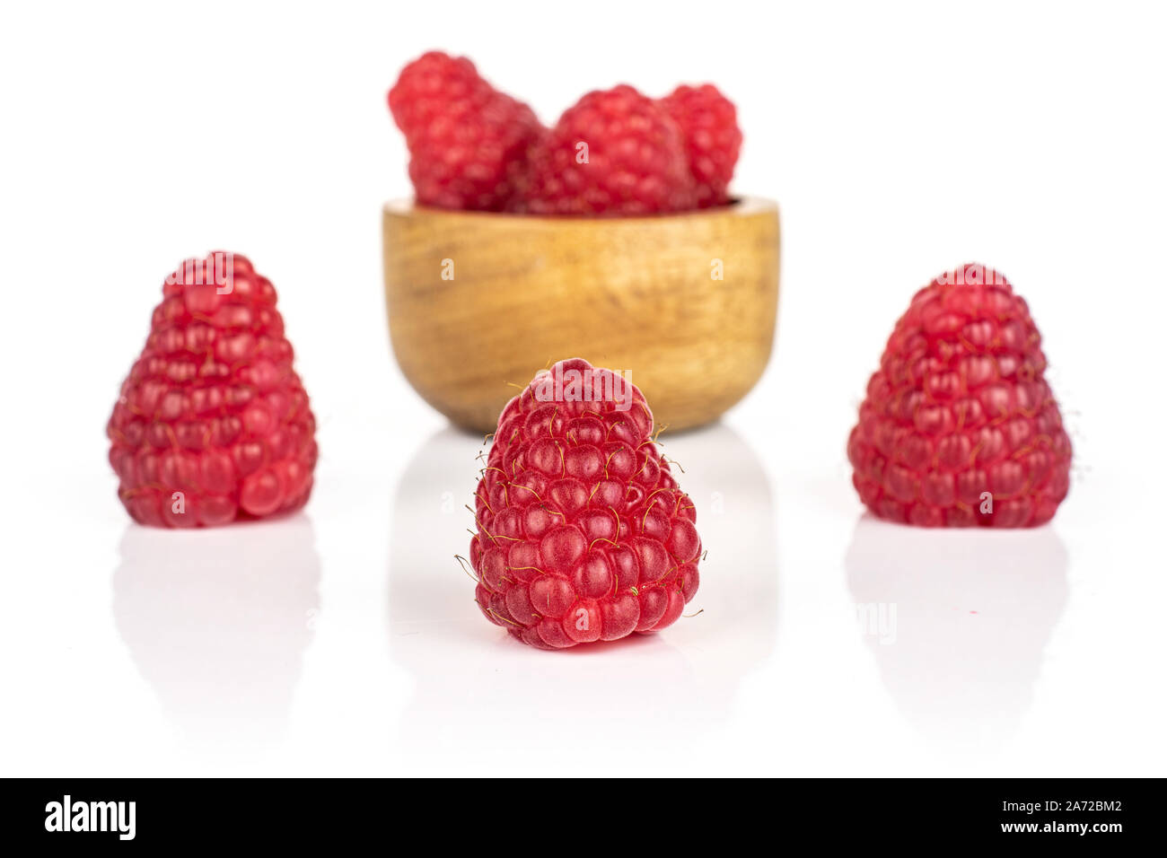 Group of six whole fresh red raspberry in tiny wooden bowl isolated on ...