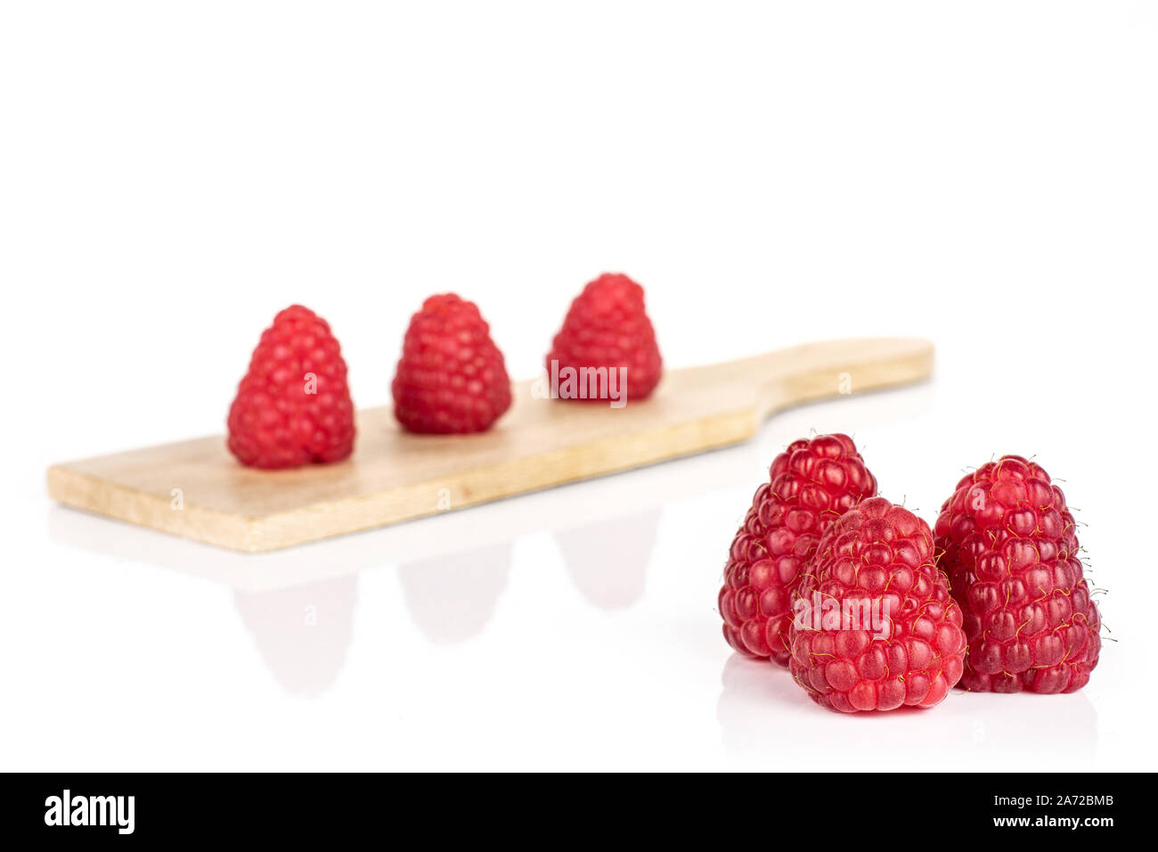 Group of six whole fresh red raspberry on small wooden cutting board ...