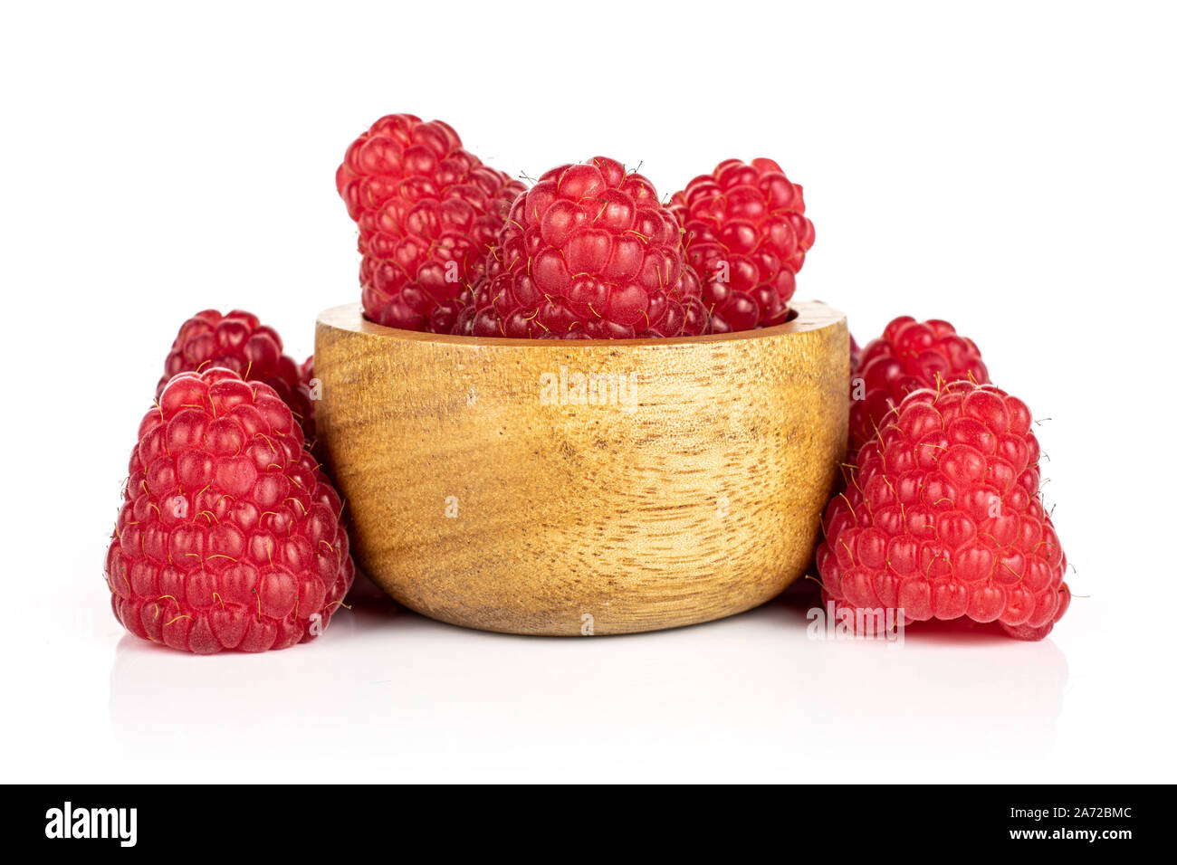 Group of seven whole fresh red raspberry in tiny wooden bowl isolated ...