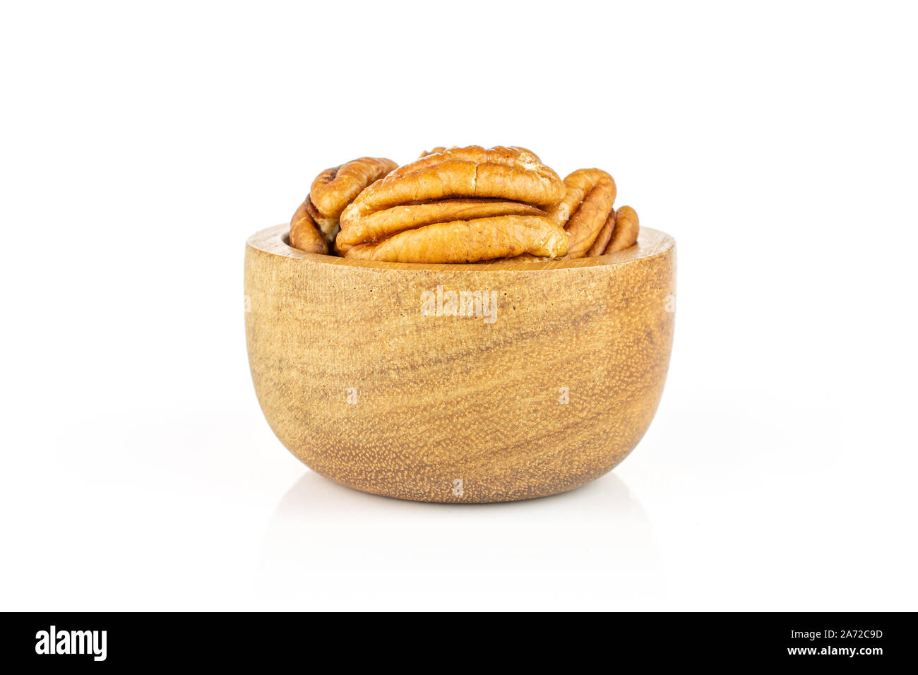 Group of four whole dry brown pecan nut in tiny wooden bowl isolated on ...