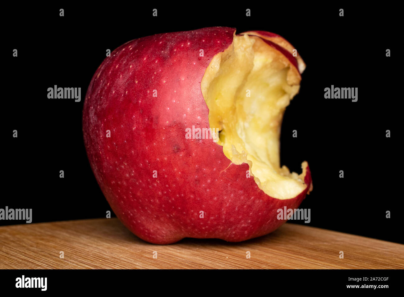 One whole bitten fresh apple red delicious on bamboo cutting board ...
