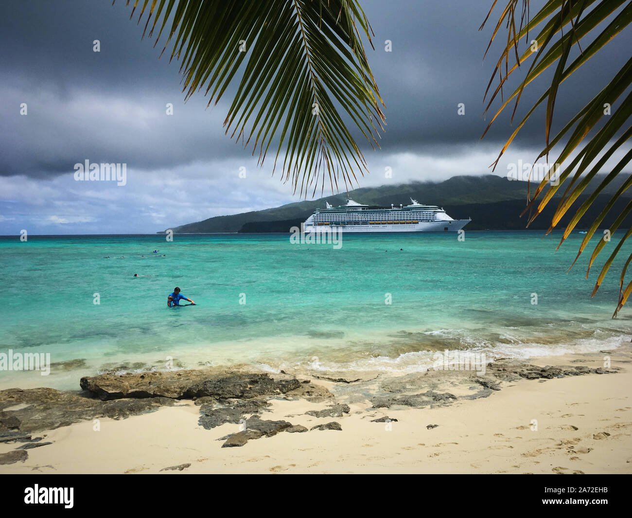 A large Carnival cruise ship moored in an inlet of Vanuatu island just ...