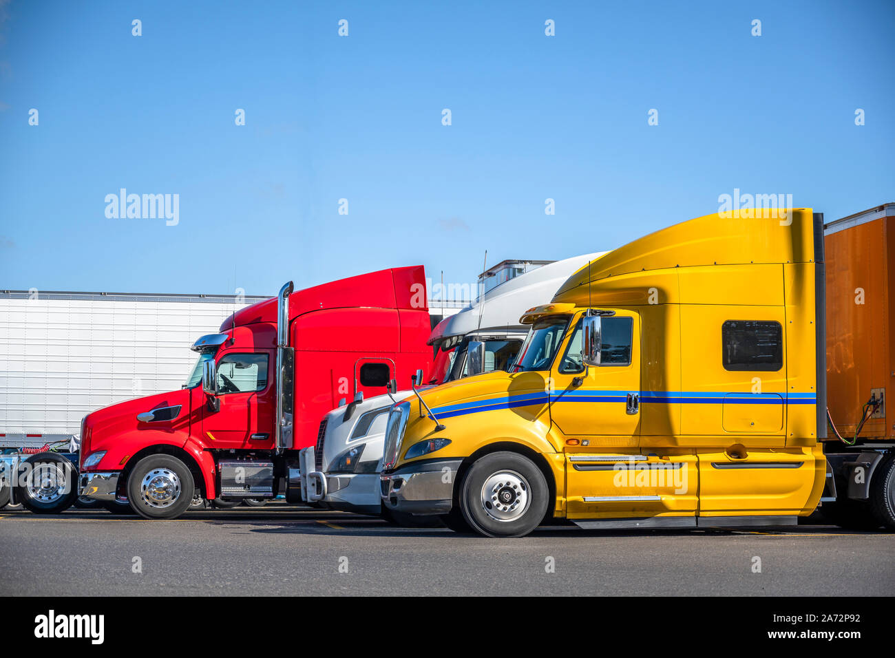 Different makes and colors of big rigs semi trucks with semi trailers ...