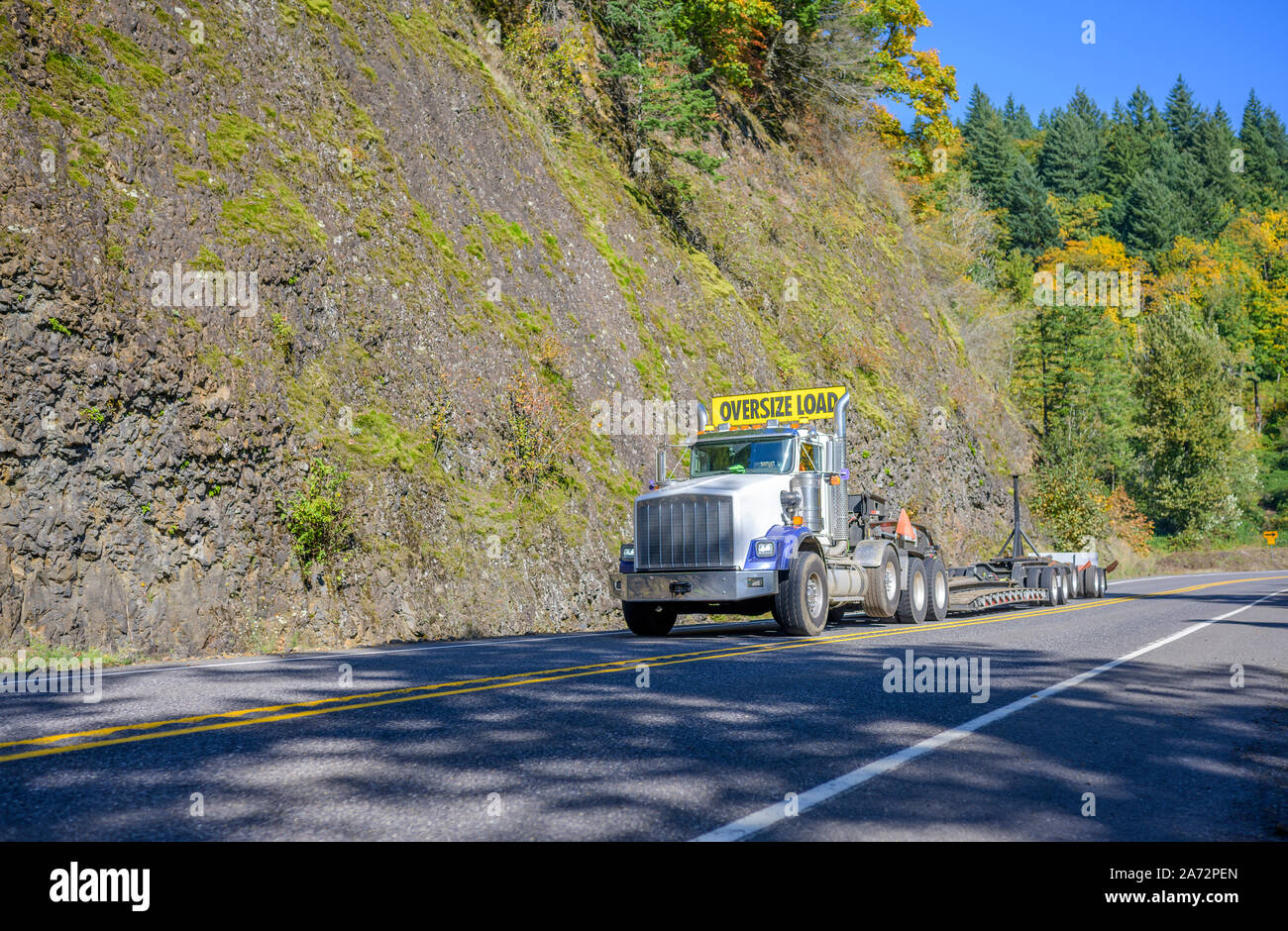 Big rig powerful semi truck transporting oversize cargo on step down ...