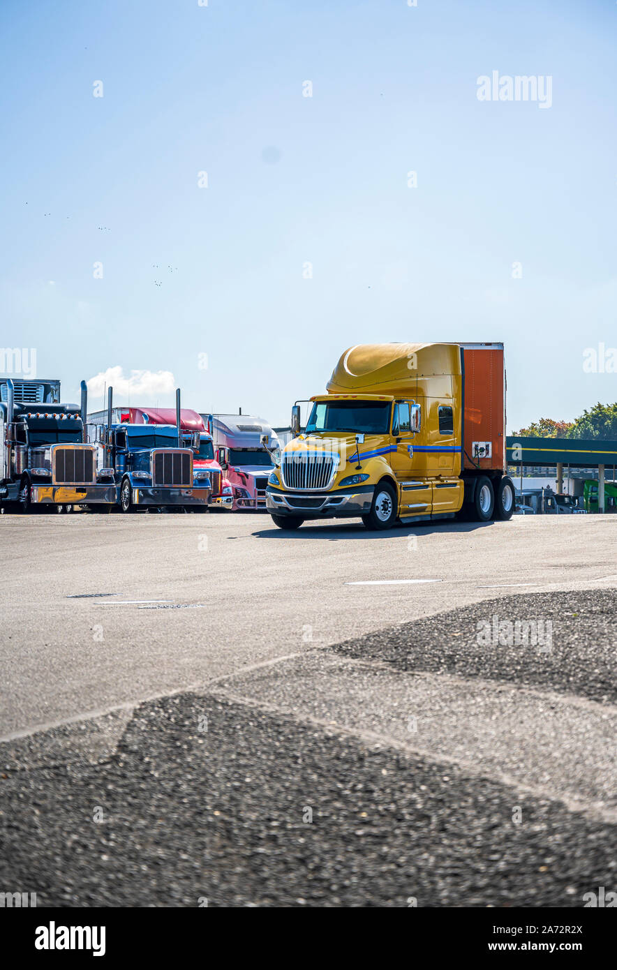 Yellow big rig commercial semi truck with orange dry van semi trailer ...