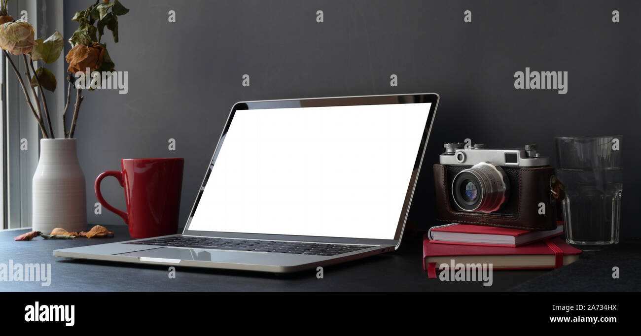 Dark trendy workspace with laptop computer and camera on black desk and ...