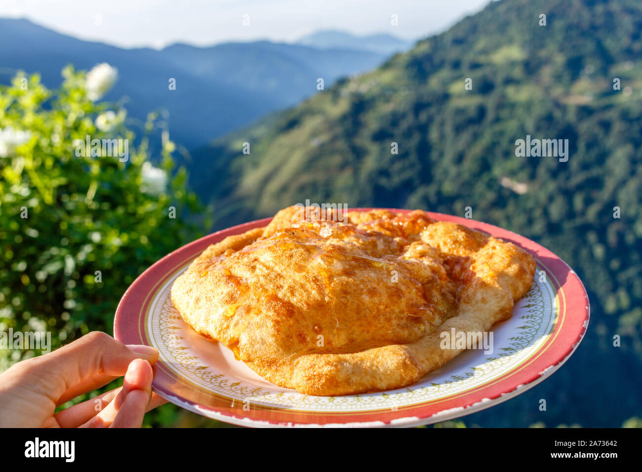 A hand holding Numtrak balep, Tibetan deep fried bread, with mountain ...