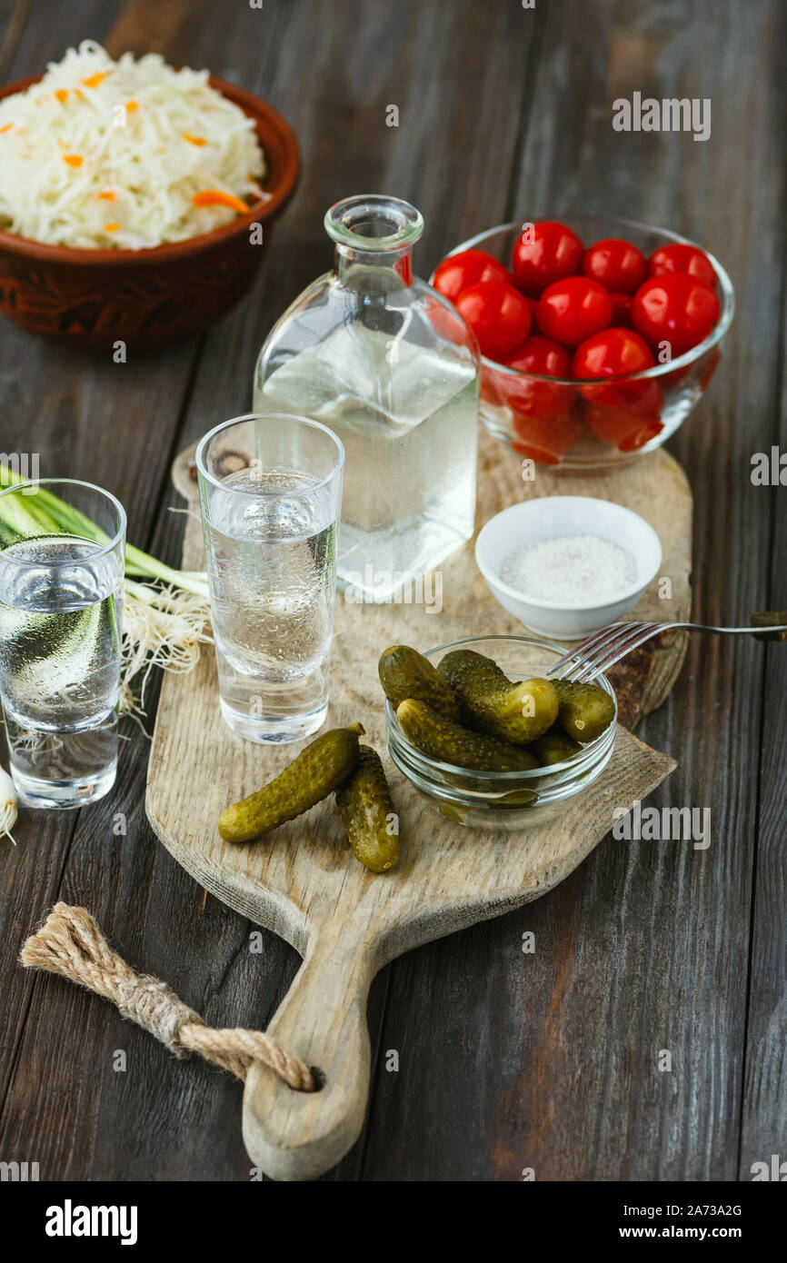Vodka with salted vegetables on wooden background. Alcohol pure craft ...