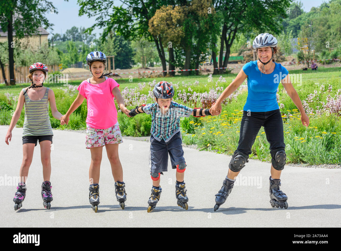 Young family doing a tour on inline skates in urban park at a sunny ...