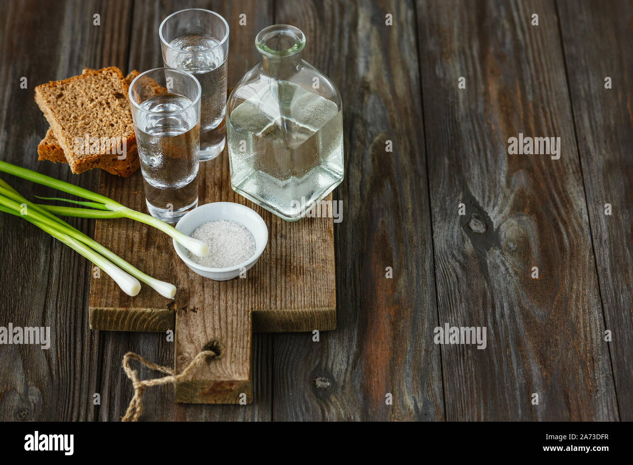Vodka with green onion, bread toast and salt on wooden background ...