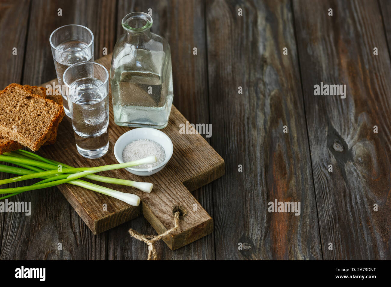 Vodka with green onion, bread toast and salt on wooden background ...