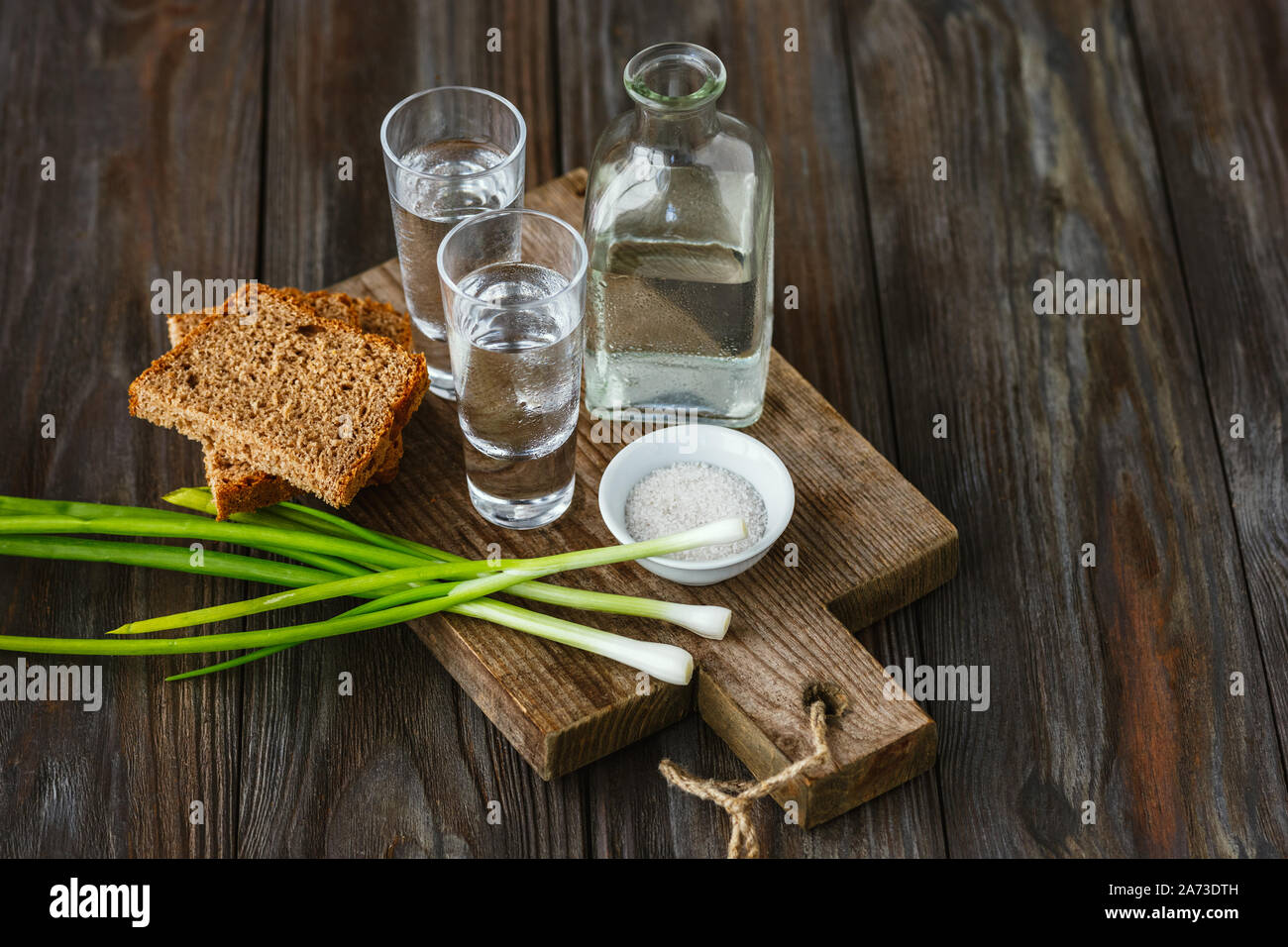 Vodka with green onion, bread toast and salt on wooden background ...