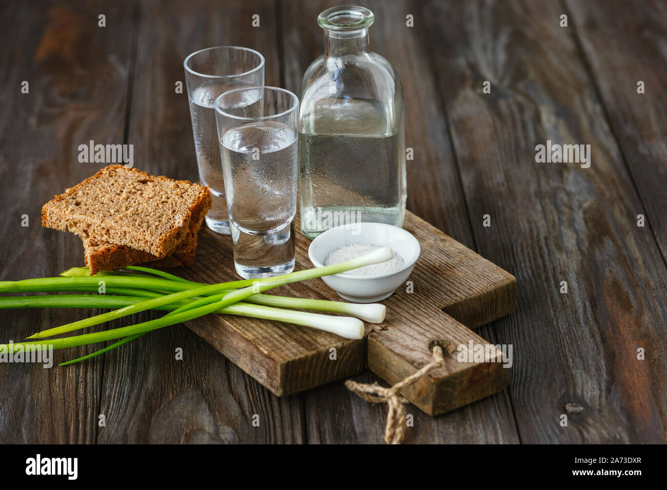 Vodka with green onion, bread toast and salt on wooden background ...