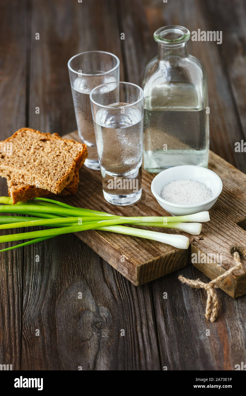 Vodka with green onion, bread toast and salt on wooden background ...