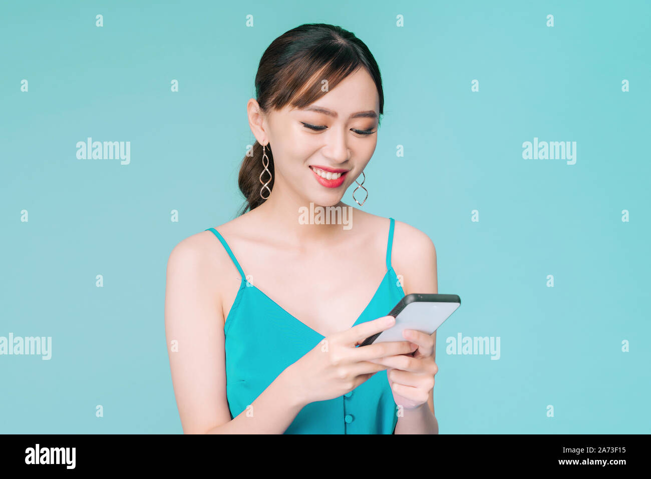 Attractive woman using text messaging feature on her portable device in studio Stock Photo - Alamy
