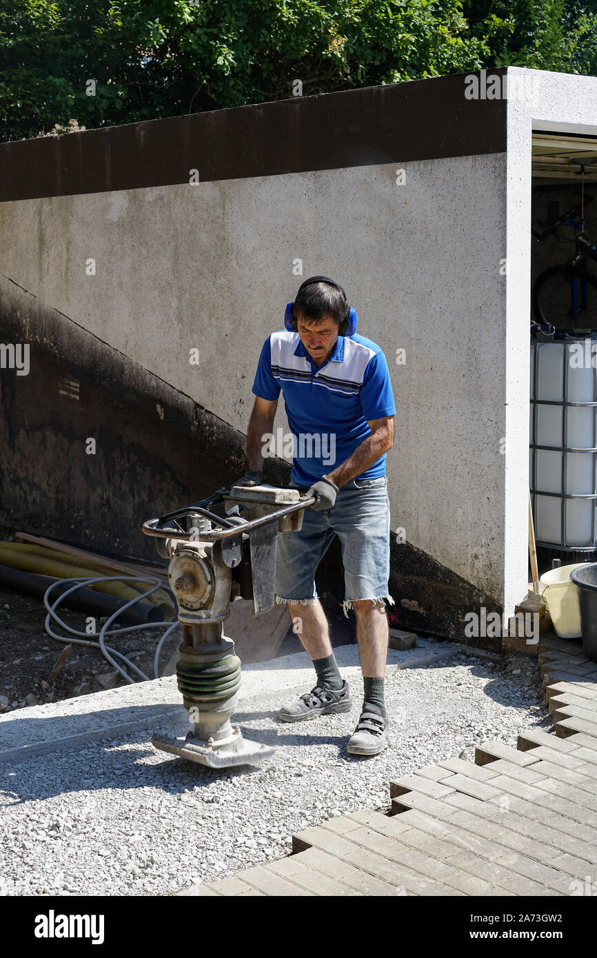 Construction worker compacting soil using compactor. Work with tamping ...