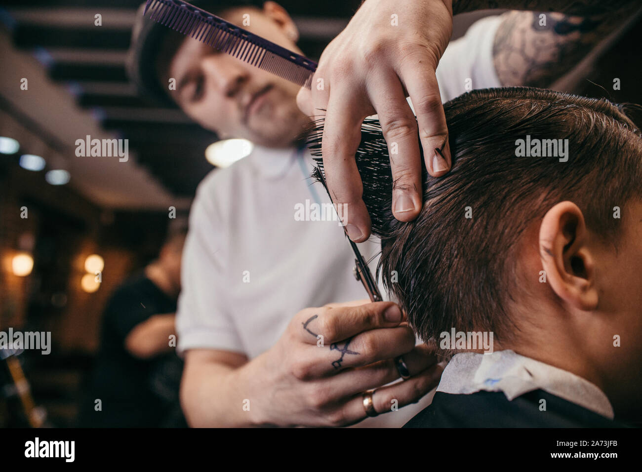 Teenage boy haircuts hairdresser in the Barber shop. Fashionable ...