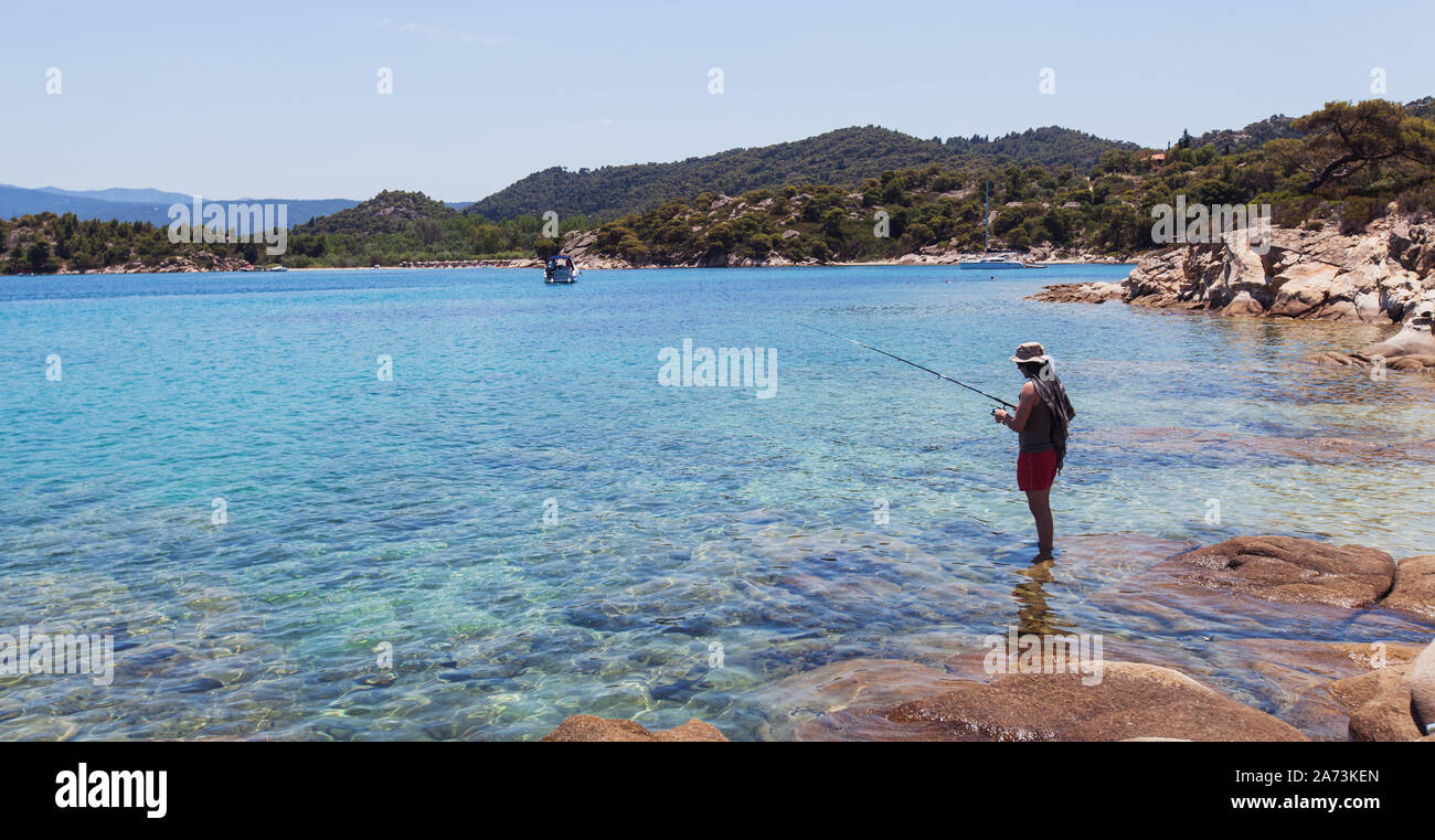 Unrecognizable man fishing in the sea bay at summer day . Beautiful ...