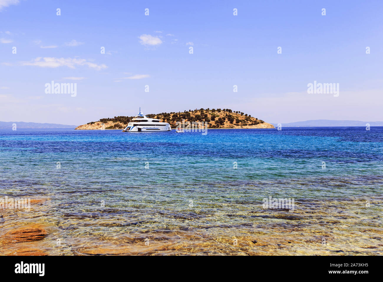 Summer landscape of small island and yacht in blue color of sea water ...