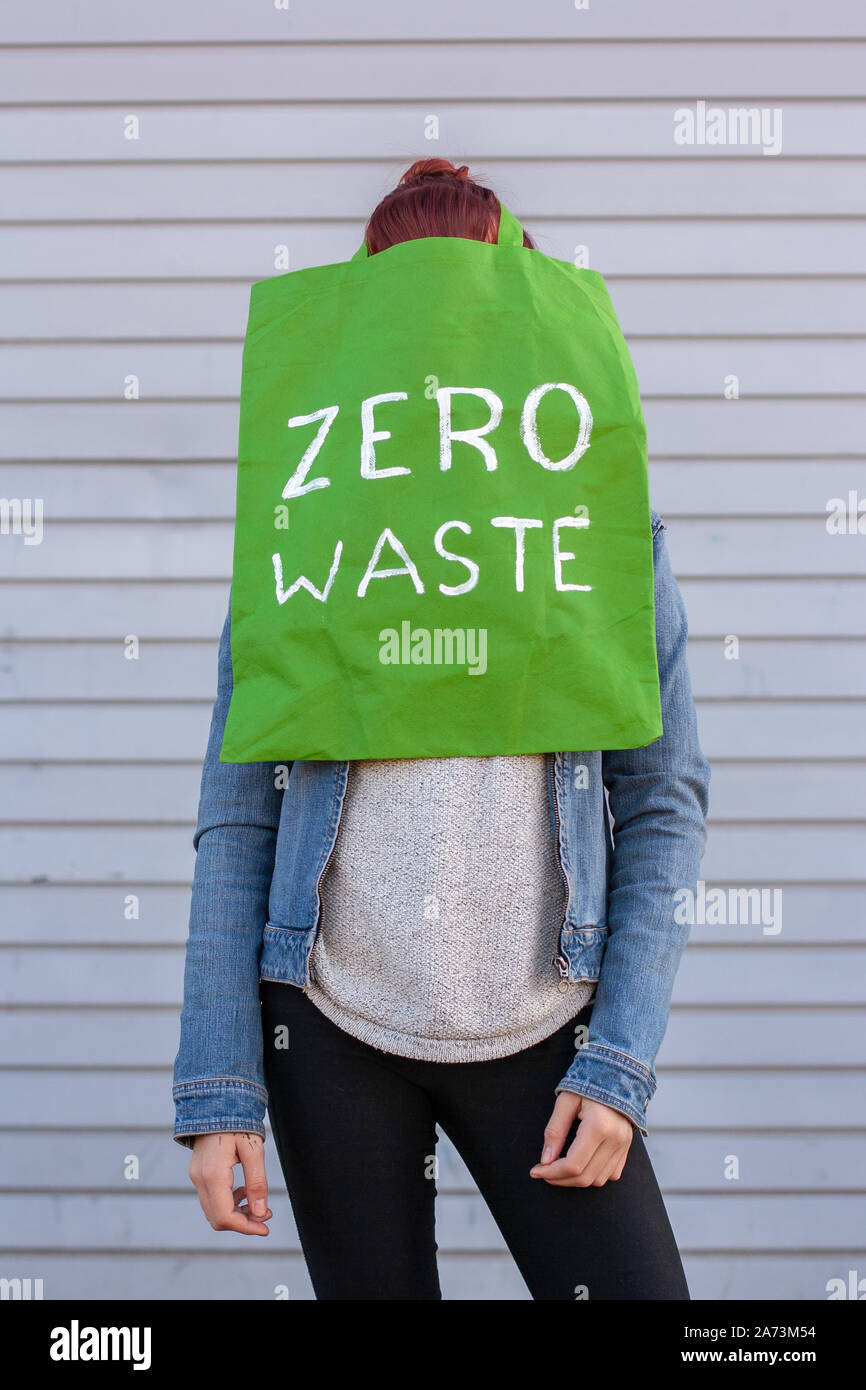 A girl stands with a hanging textile eco bag with the inscription zero ...