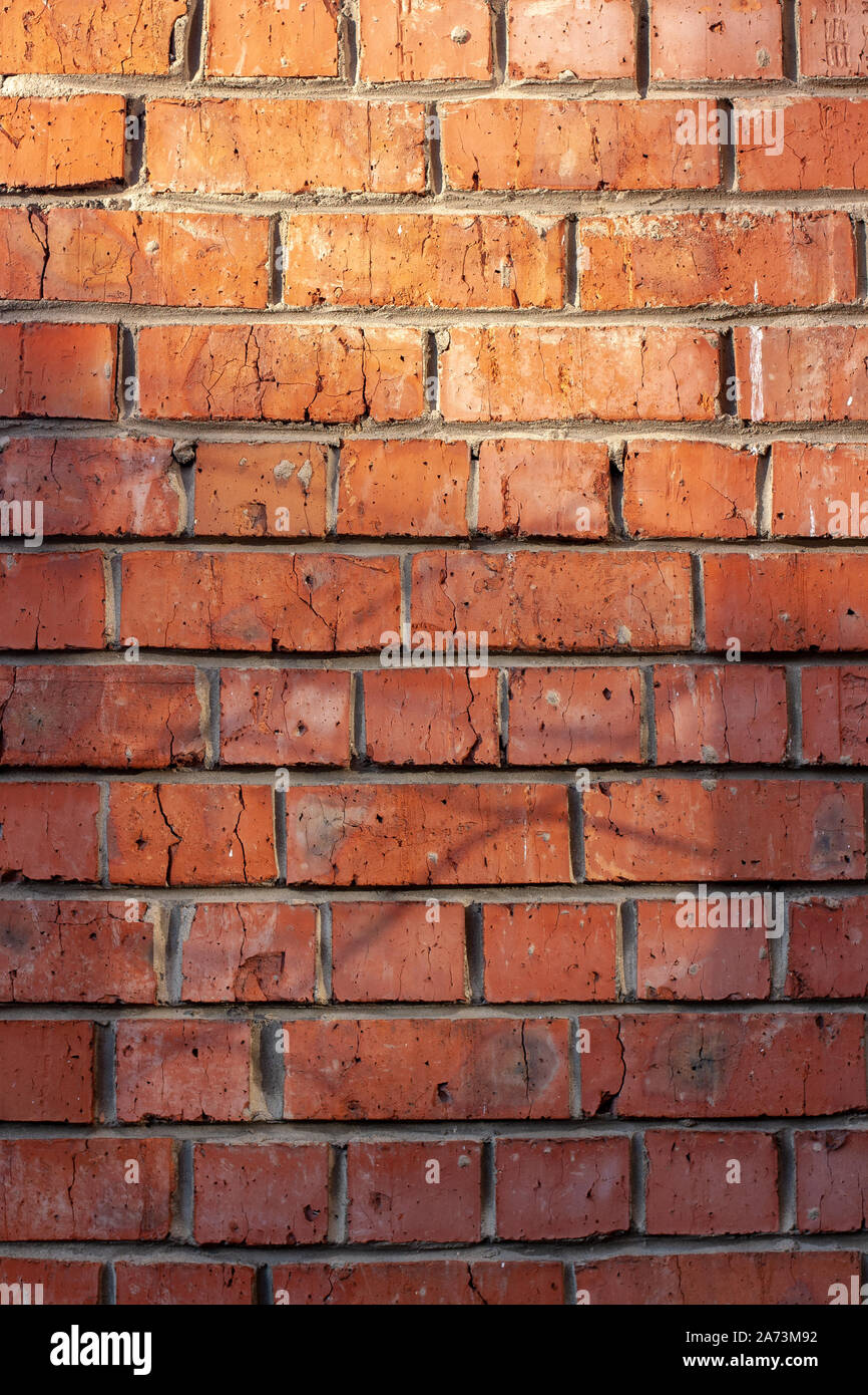 Texture red brick wall with sun flare from the window. Crooked old ...