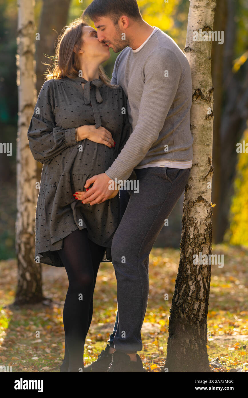 Loving pregnant young couple kissing tenderly as they clasp hands ...