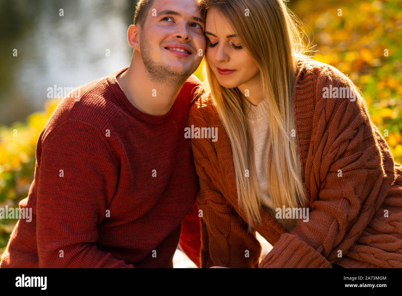 Loving couple sitting with cheeks touching as they relax together on a ...