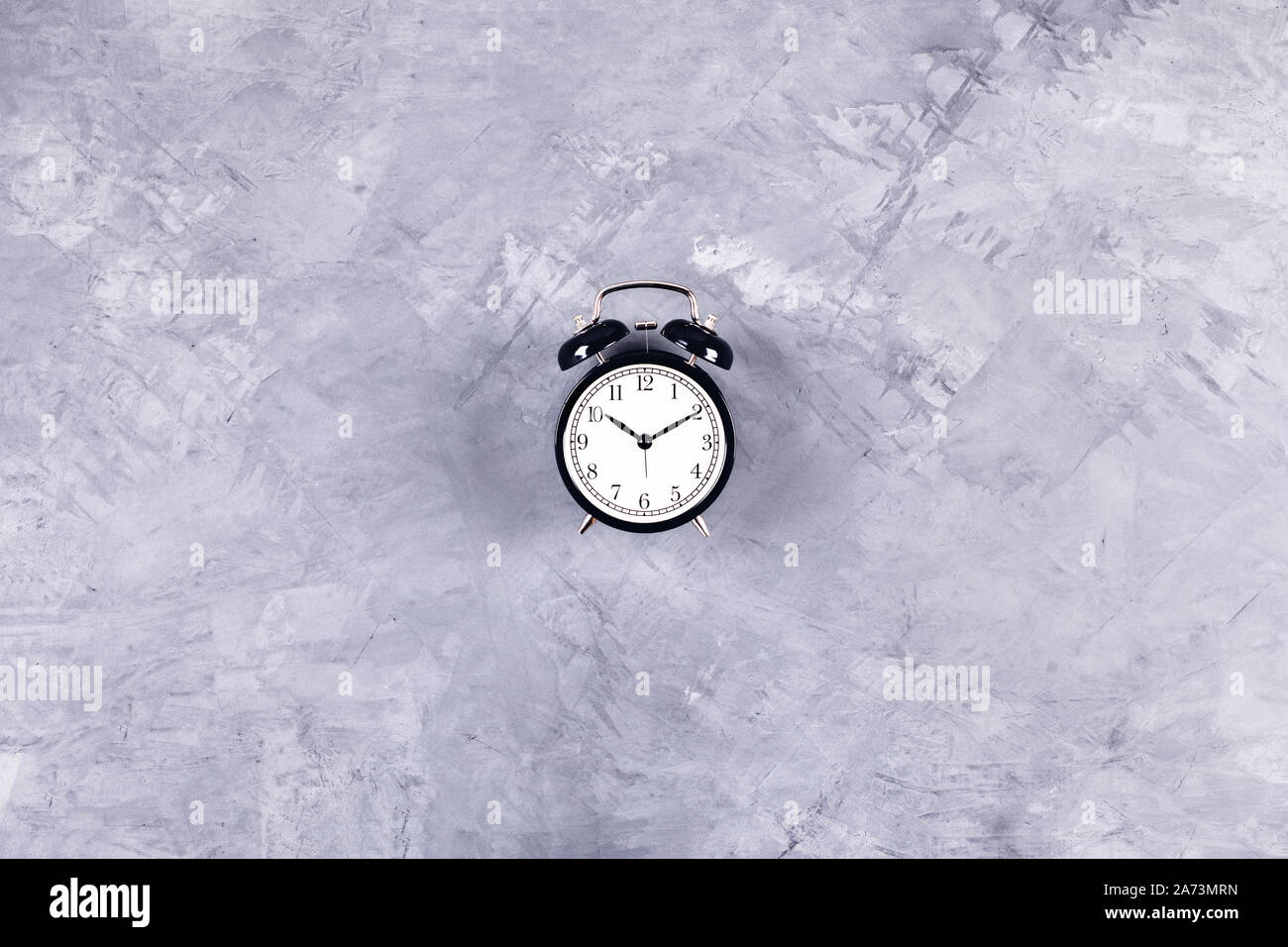 Black vintage clock with alarm on gray concrete background. Flat lay ...