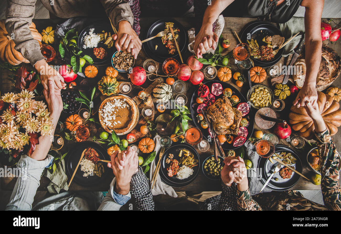 Family or friends praying holding hands at Thanksgiving celebration ...