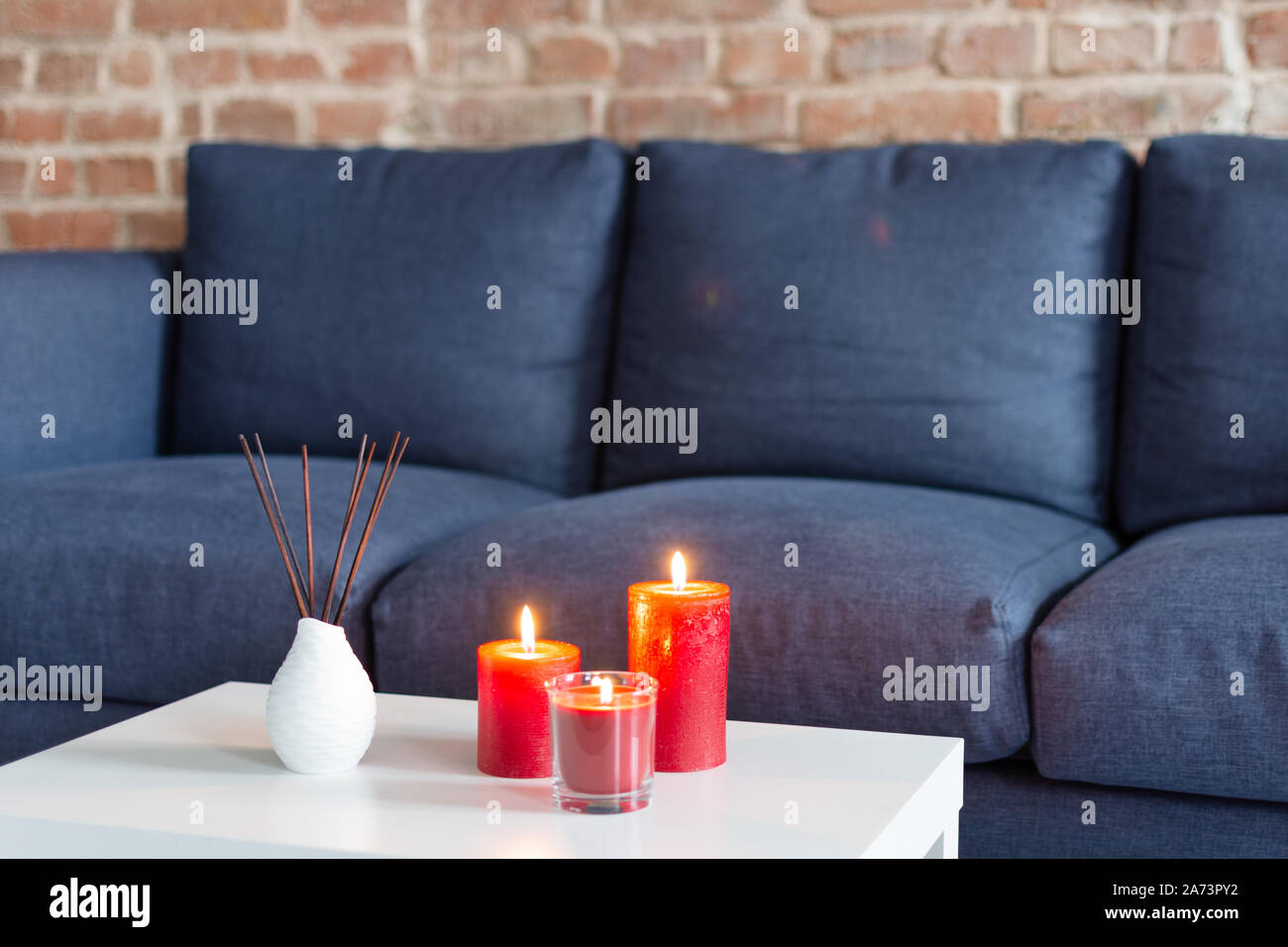 Room air refresher sticks and red burning candles on table on home ...