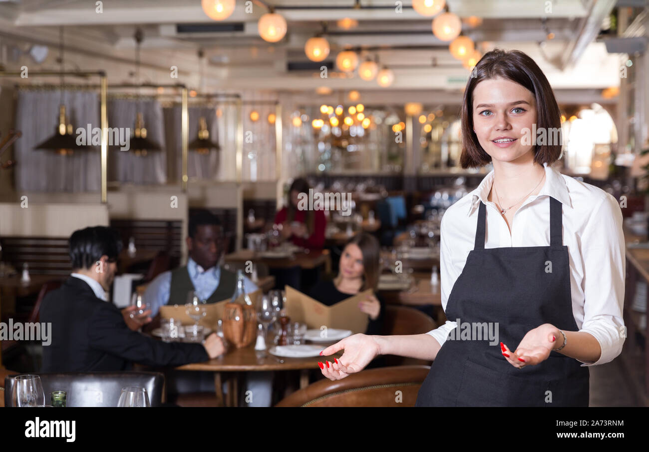 Woman waiter is welcoming clients in hall of luxurious restaurant Stock ...