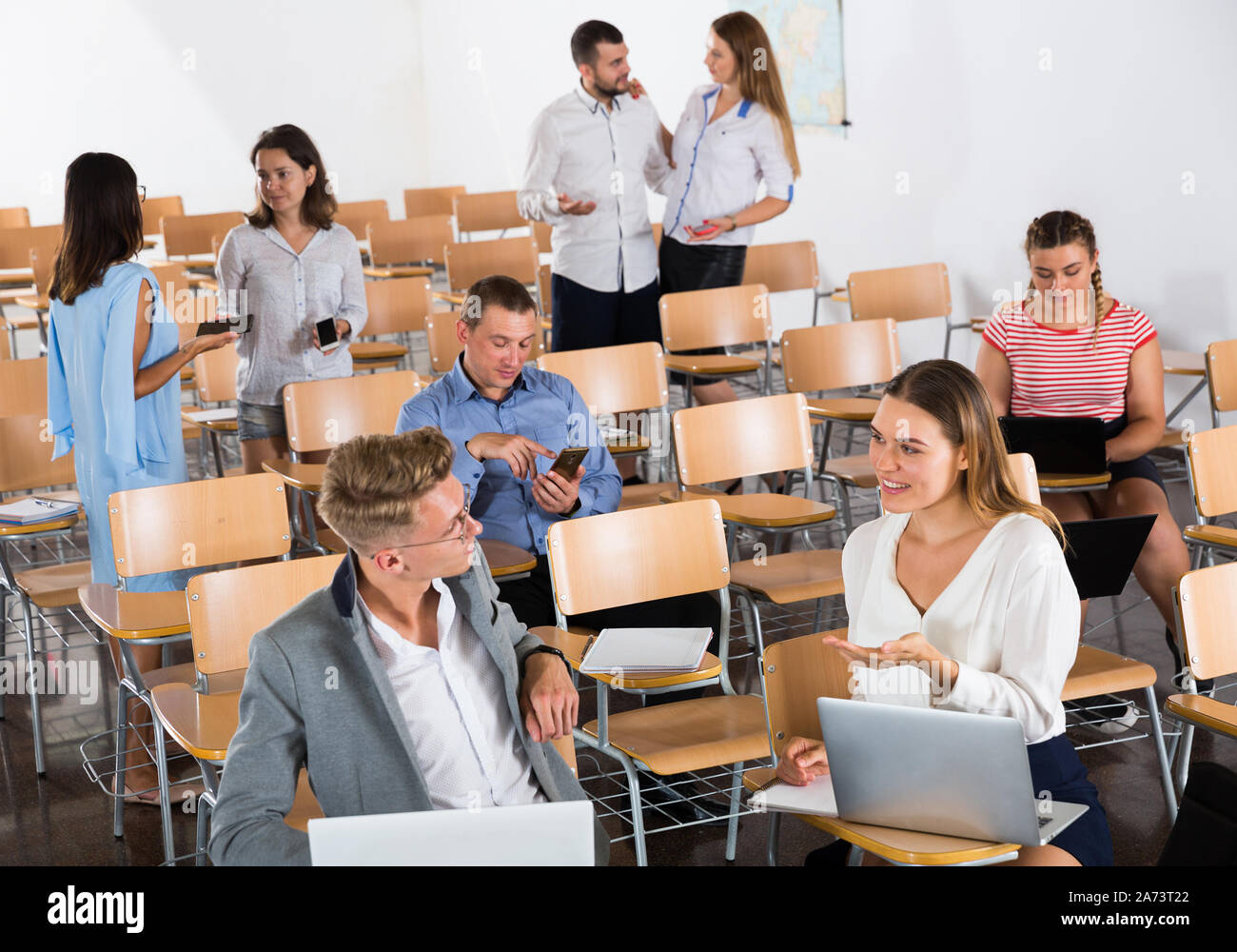 Friendly student group talking in classroom having break between ...