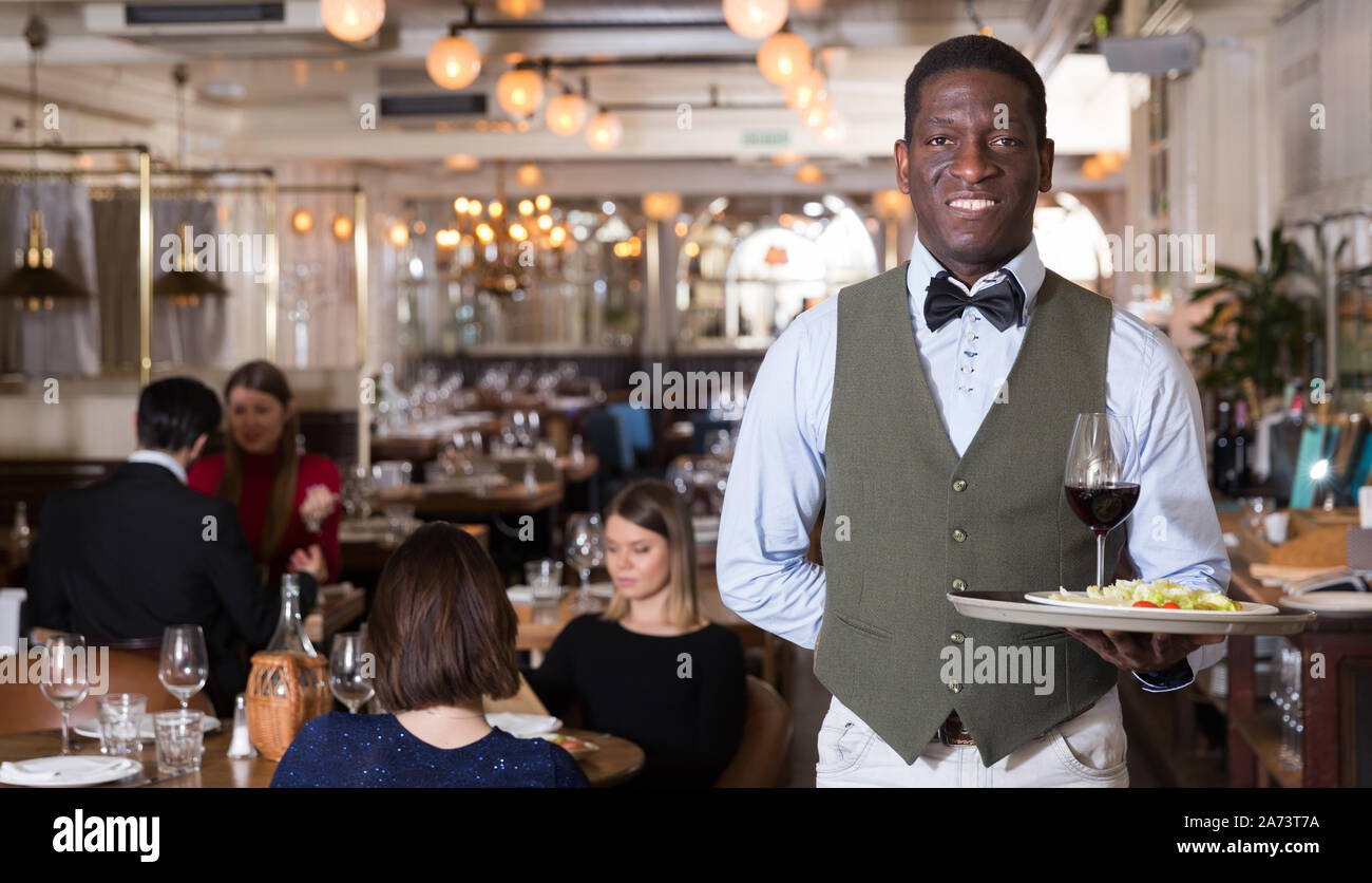 Man waiter is standing with order in hall of luxurious restaurant Stock ...