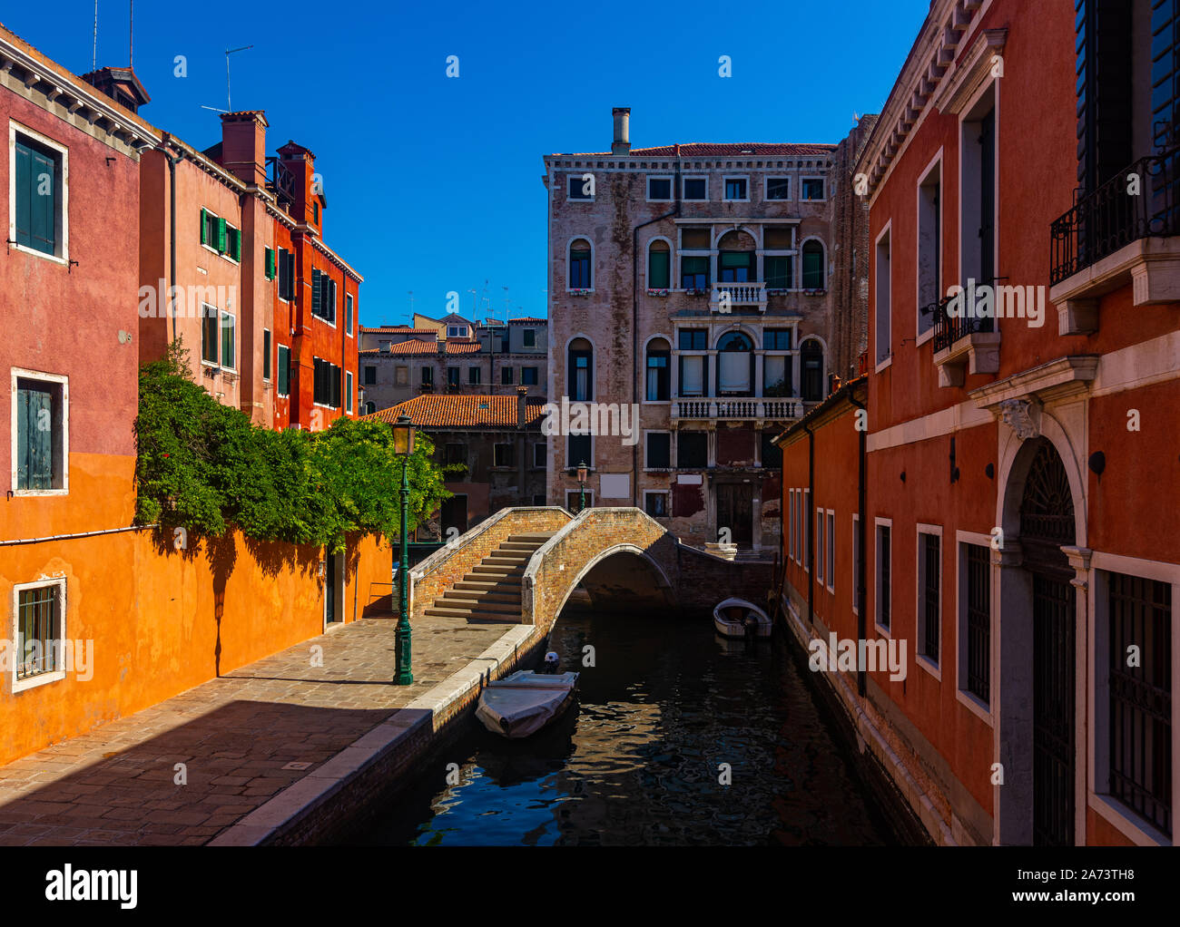 Traditional Venice cityscape with narrow canal, moored boats and ...