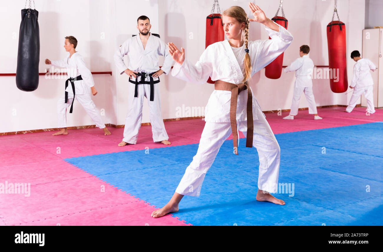 Tween positive girl mastering new taekwondo moves during group class ...