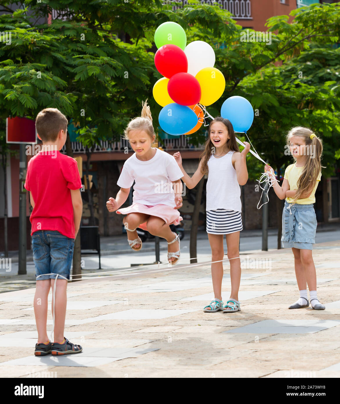 Happy small kids in school age playing together with chinese jumping ...