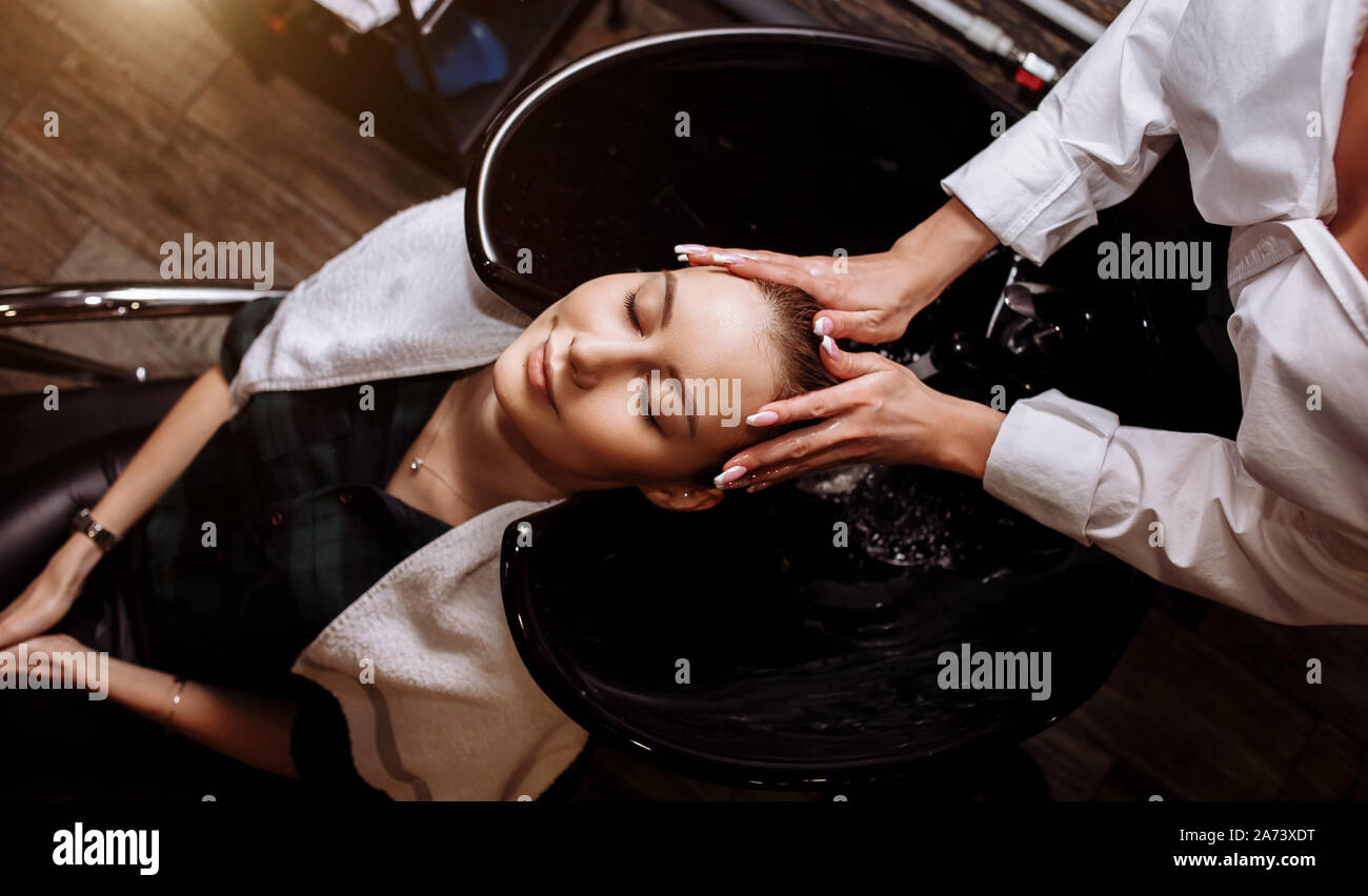 Gorgeous cute young woman enjoying head massage while professional ...