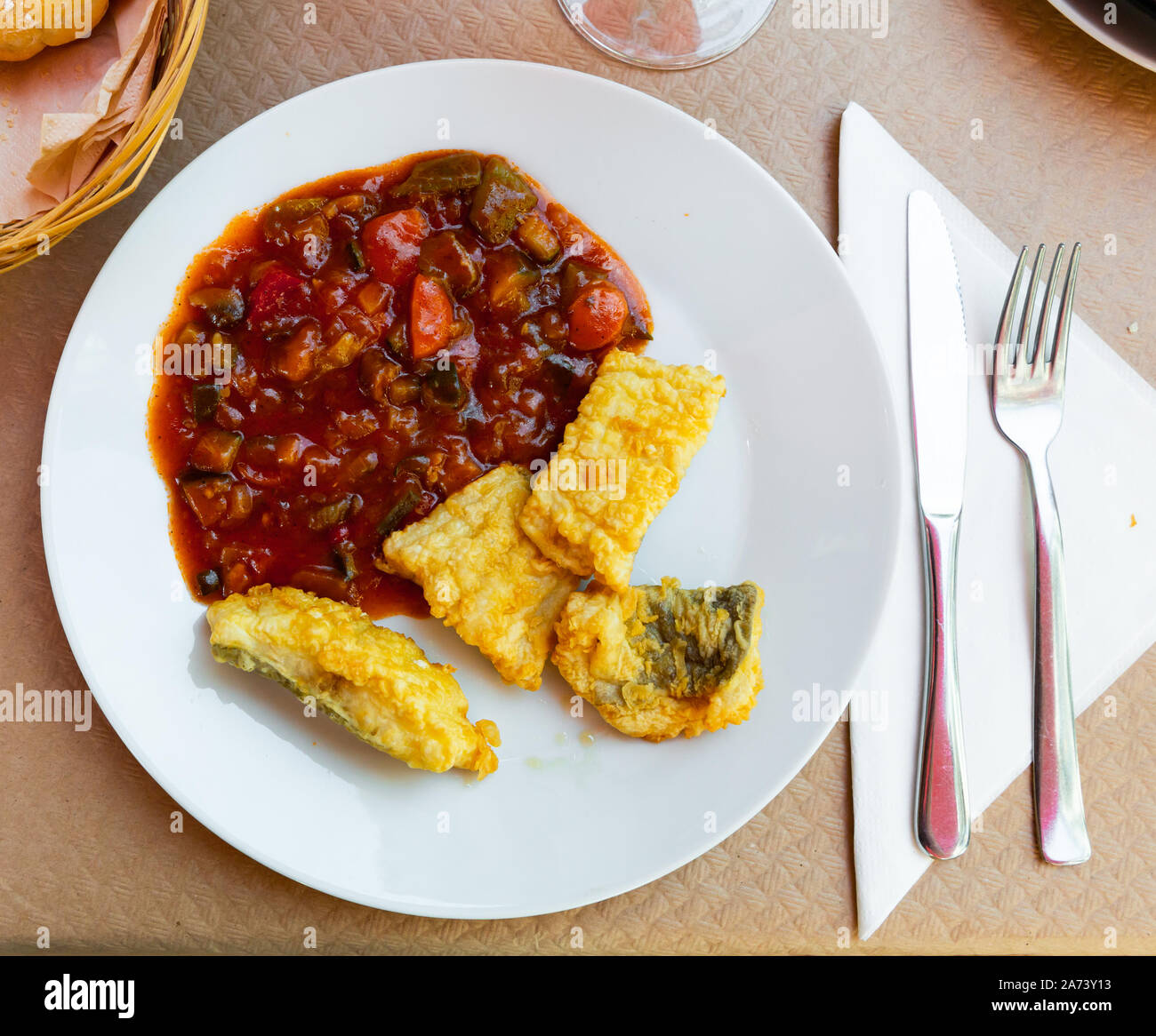 Spanish dish – breaded codfish served with vegetable stew on plate ...
