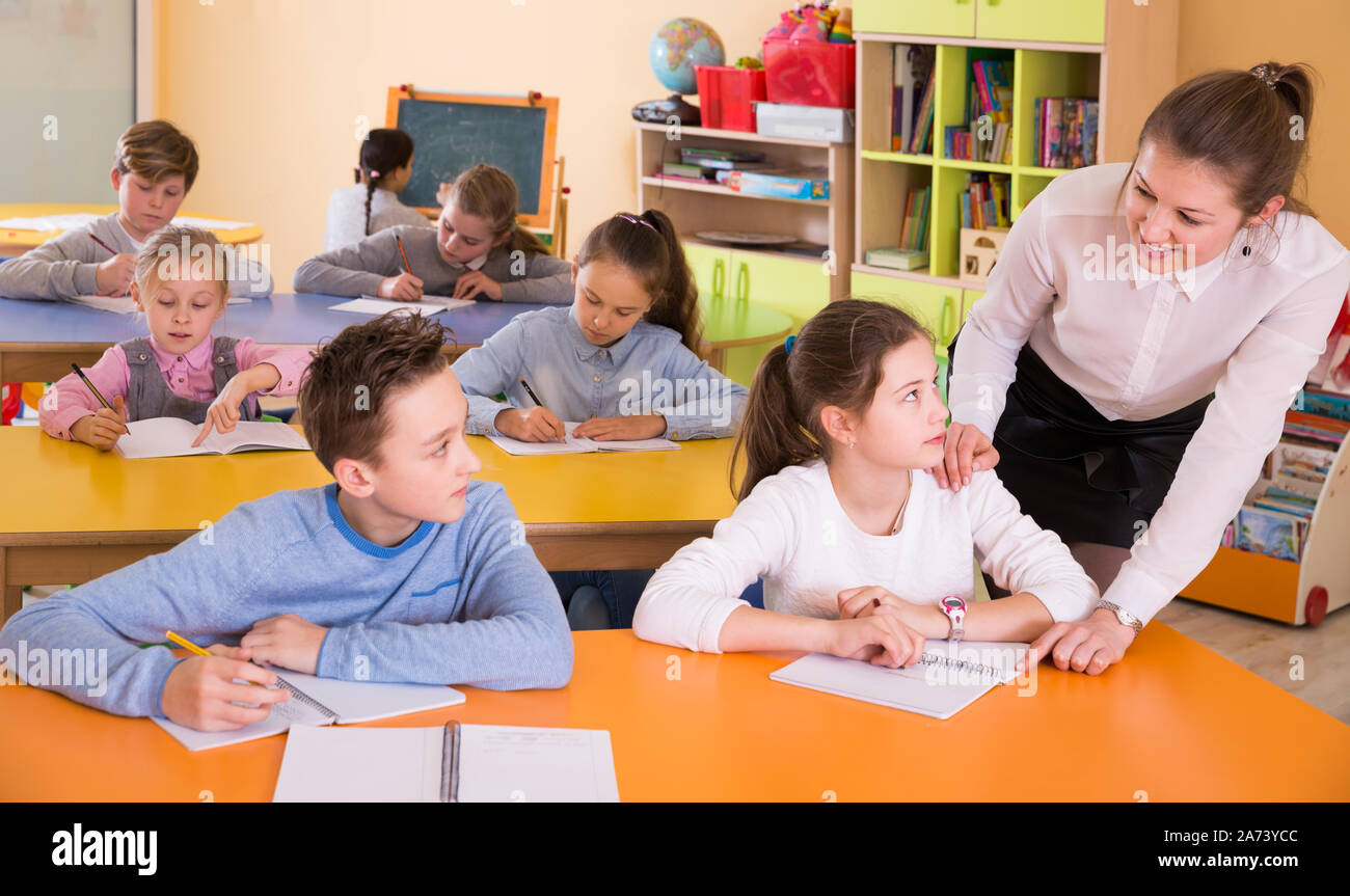 Young teacher helping to elementary age children studying at class ...
