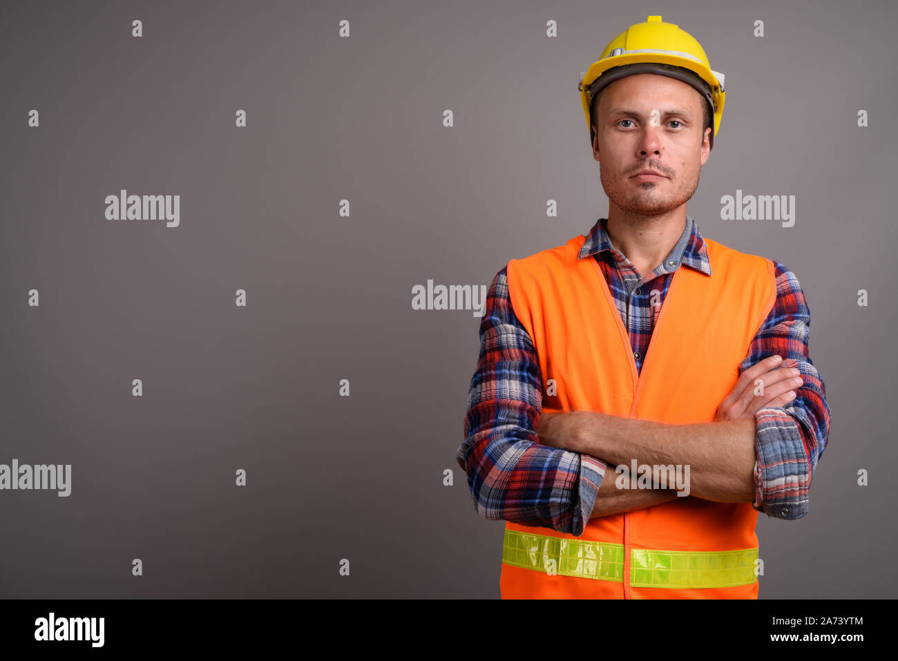 Portrait of handsome man construction worker against gray background ...