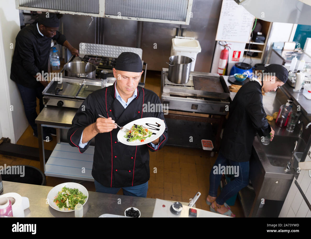 Head chef checking dishes in kitchen of restaurant before serving ...