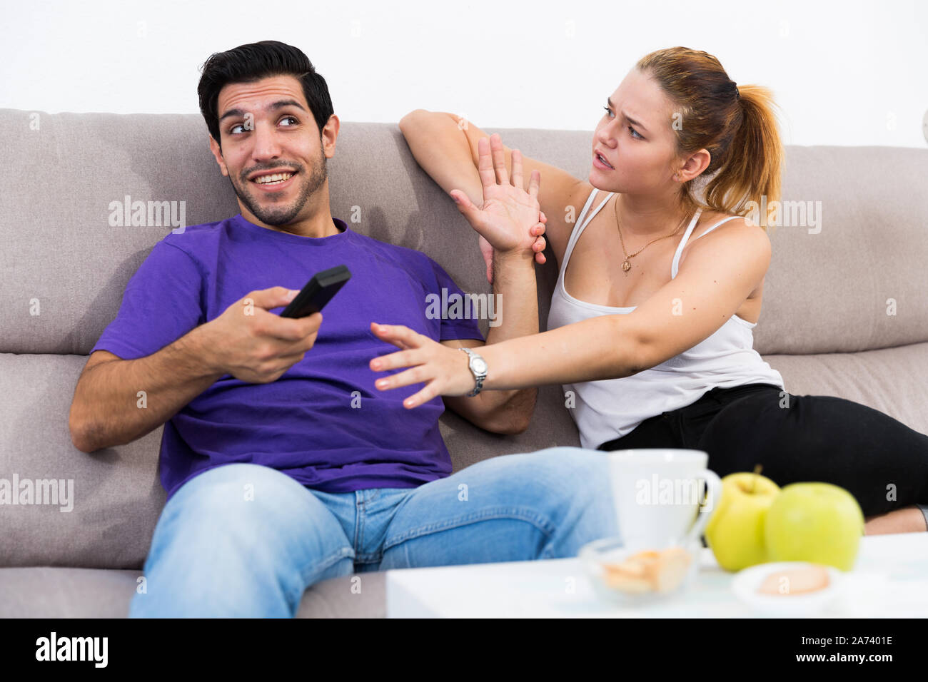 Young couple arguing because of TV remote control sitting on couch ...