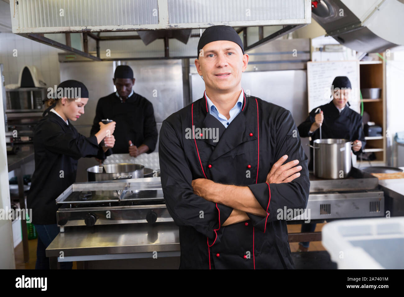 Confident chef of restaurant posing in kitchen on background with ...