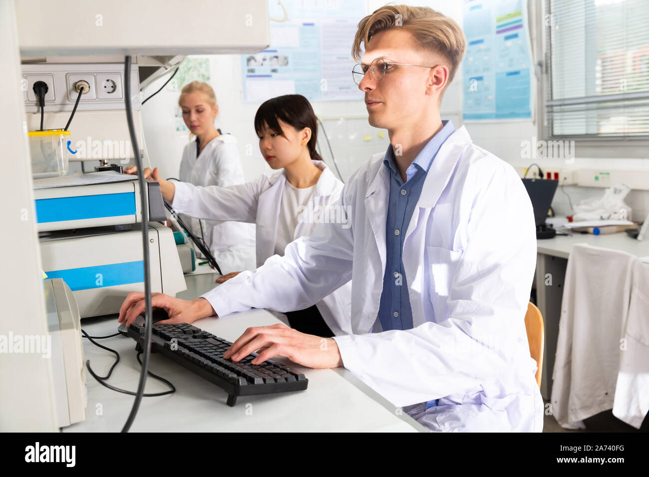 Portrait of male and female scientists in white coats working at ...