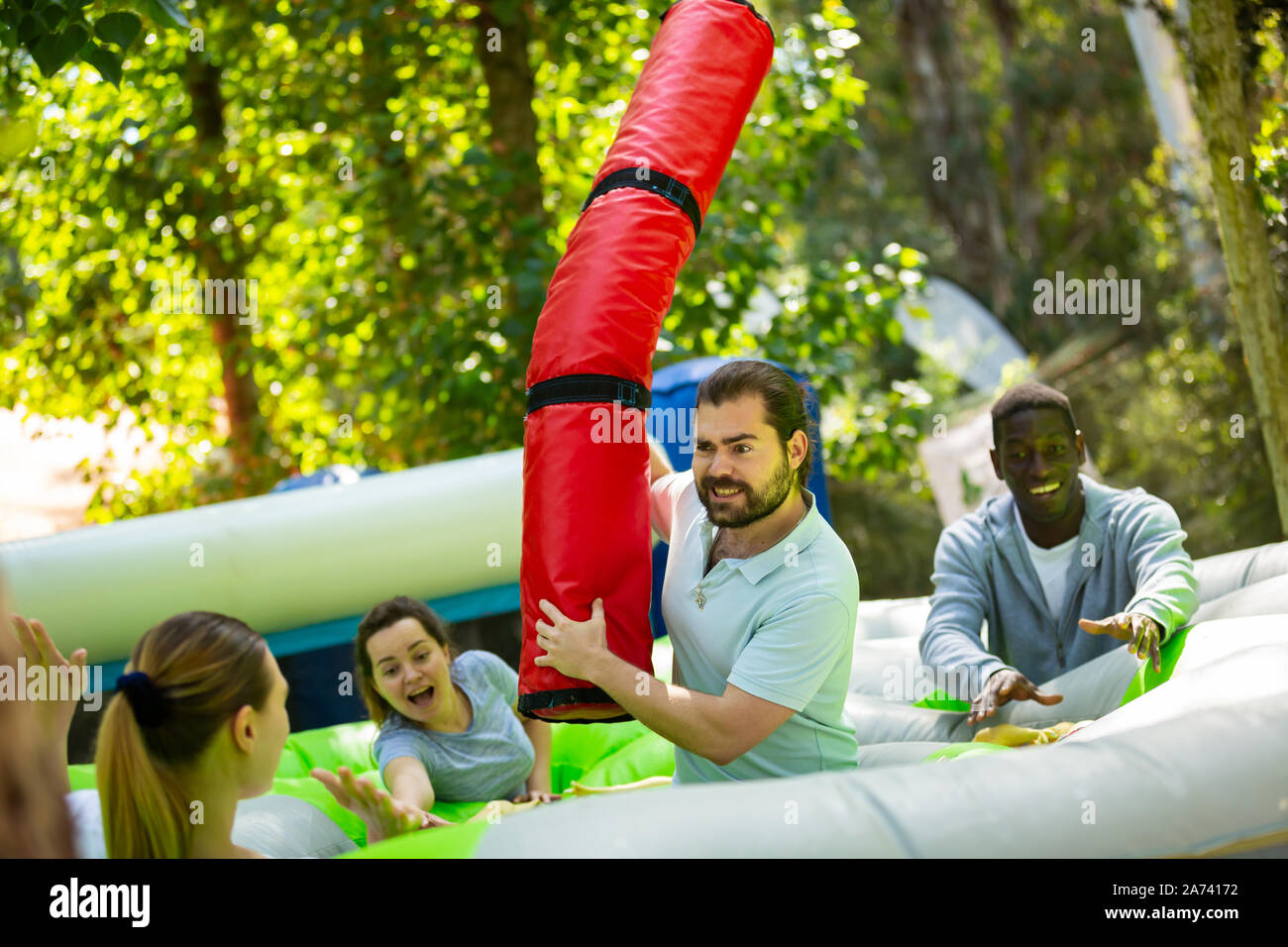 Team of friends playing with inflatable sticks on the trampoline Stock ...