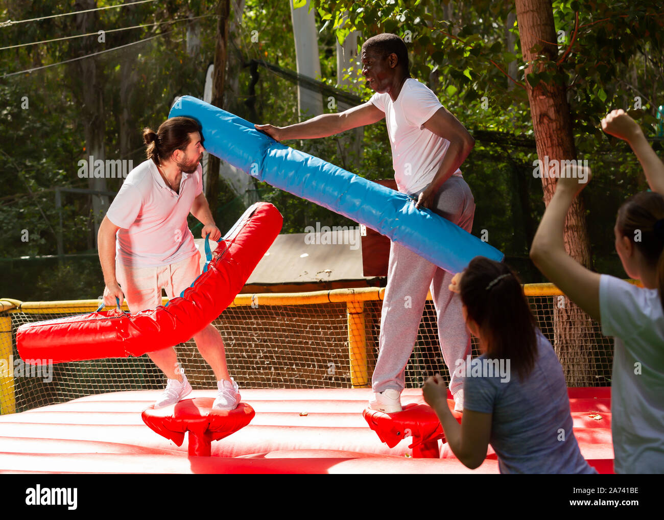 Glad adult men having fun on inflatable gladiator fight arena in ...