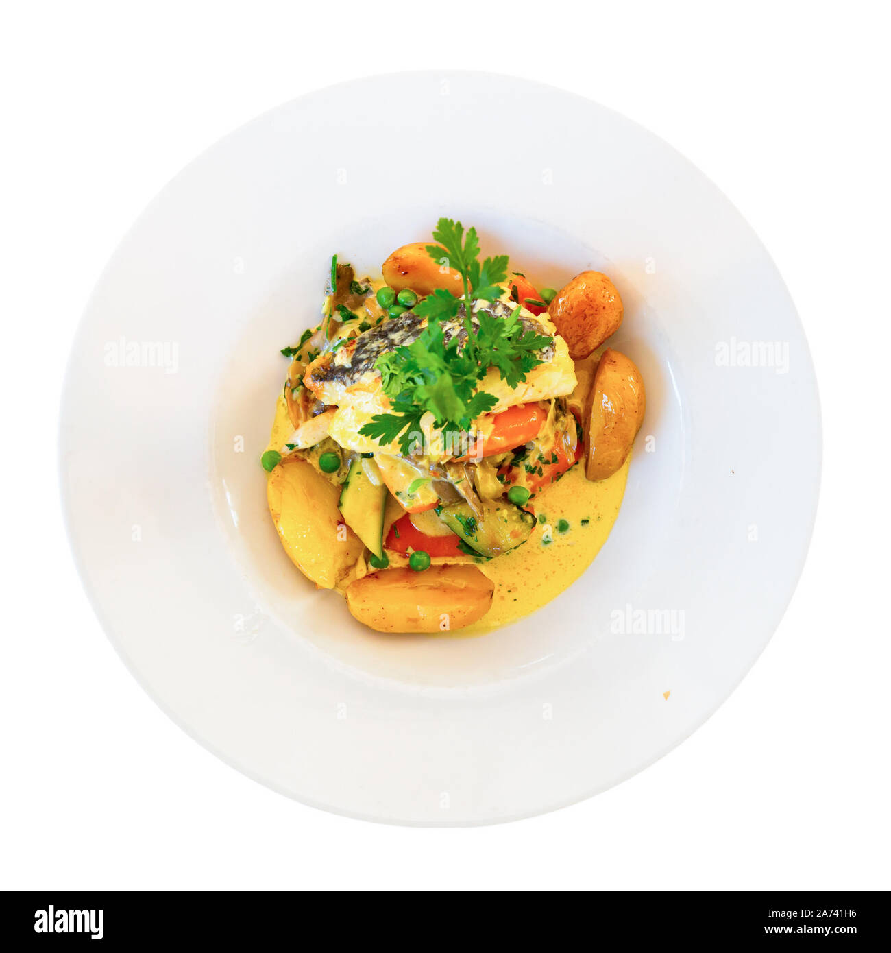 Spanish style hake steak served with baked vegetable and creamy sauce ...